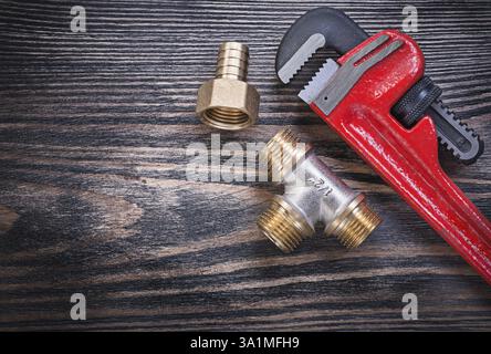 Metal pipe wrench brass equal tee hose nipple on wooden board Stock ...