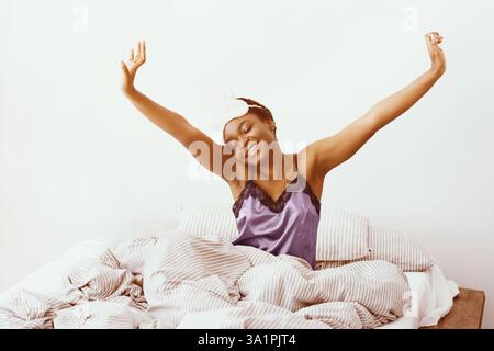 Happy and relaxed after good night sleep. Young Black lady in pink ...