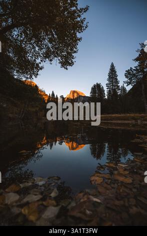 HALF DOME is reflected in the MERCED RIVER during the fall season ...