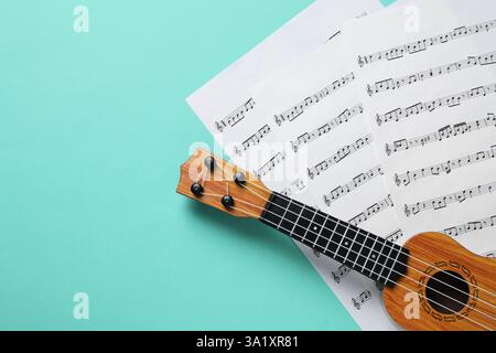 Ukulele and music sheets on turquoise background, closeup Stock Photo ...