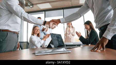 Doing handshake. Group of office workers are together indoors Stock ...