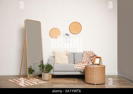 Sofa, table and floor mirror near white wall in interior of room Stock ...