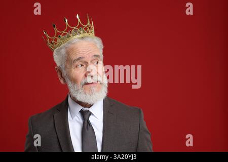 Senior man wearing luxury crown on orange background Stock Photo - Alamy