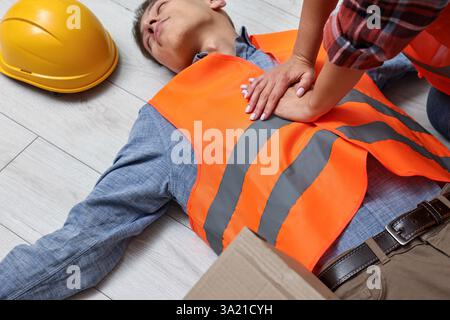 Accident at work. Woman performing CPR on her unconscious colleague in ...
