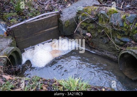 Small water gate with foamy stream in early spring Stock Photo - Alamy