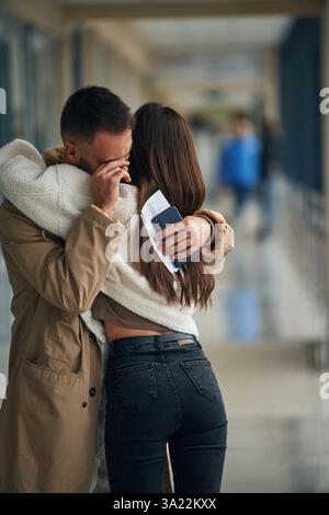 Man is crying, embracing, farewell. Couple are in the airport hall ...