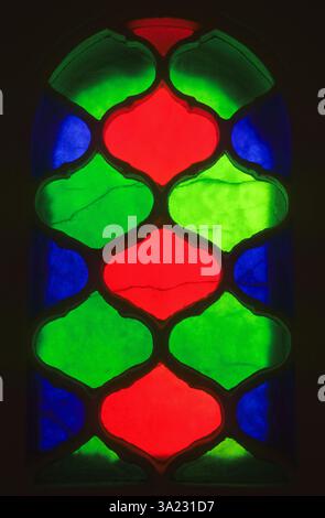 Curving red, blue and green stained glass shapes within the takhrim ...