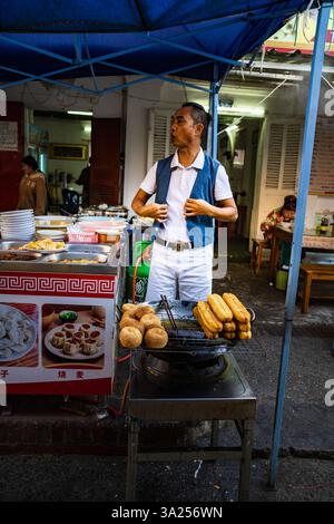 street food vendor preparing fried rice in large wok at busy outdoor ...