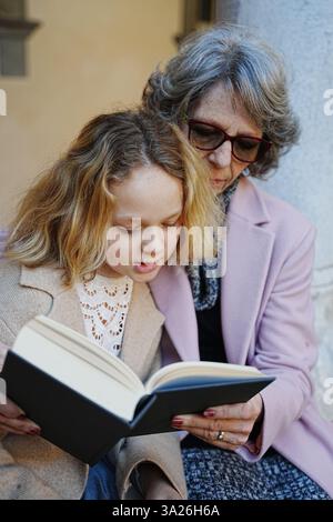 Spring. Grandmother and granddaughter reading a book in the library ...