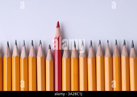 One red pencil among graphite ones on light grey background, top view ...