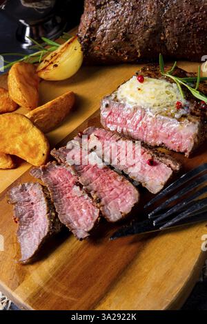 rustic medium butter beef steak with herbs and potato wedges Stock Photo - Alamy