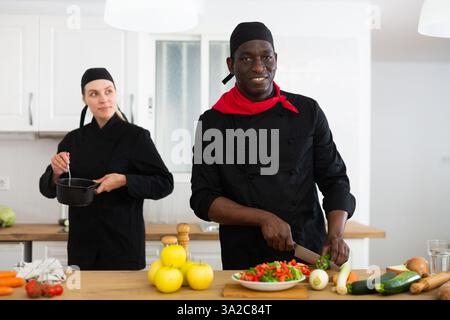 Two female and male cooks wearing uniform working on kitchen Stock ...