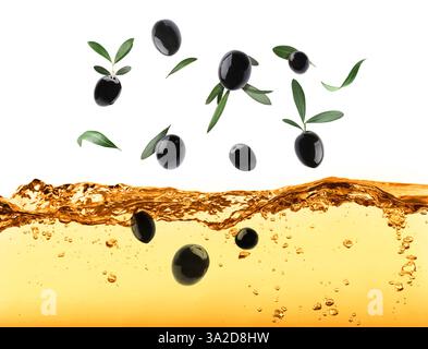 Black olives and green leaves falling into cooking oil on white ...
