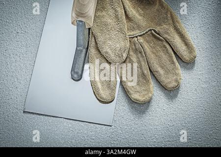 Putty knife leather protective gloves on concrete background ...