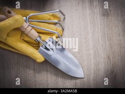 Stainless hand trowel rake yellow leather working gloves on wood board ...