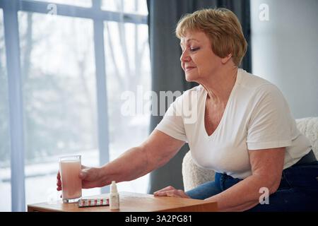Drink with anti flu medicament. Senior elderly woman is at home in the ...
