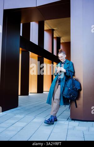 Student ginger girl near modern university building using a smartphone ...