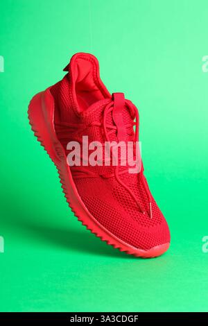Stylish red sneaker in air against green background Stock Photo - Alamy