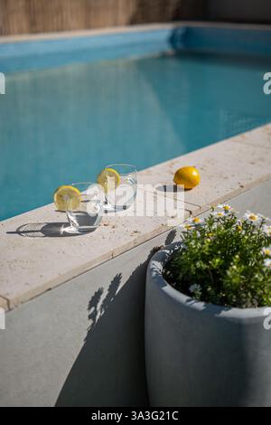 Refreshing water with lemon on edge of swimming pool, space for text ...