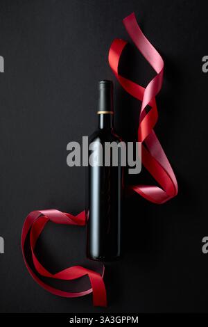 Bottle of red wine with red and pink satin ribbons. Top view. Copy ...