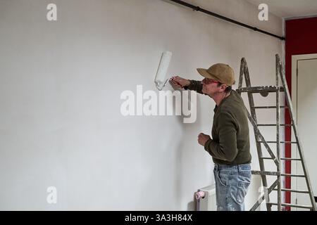 Painter in dirty clothes renovate a wall in a loft Stock Photo - Alamy