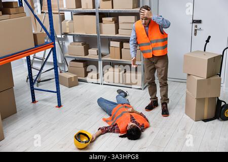 Accident at work. Worried man and his unconscious colleague in ...