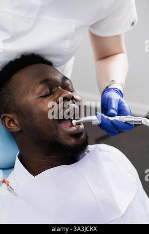 Dental drill for african man in dentistry clinic. Dentist is removing ...