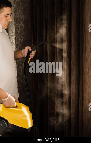 Cleaner is steaming the curtains using a professional steam machine ...