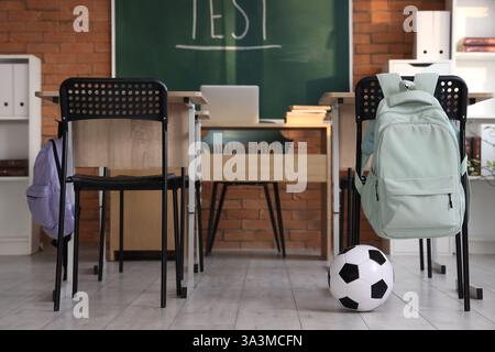 a backpack hanging on a chair in a school classroom. Back to school ...