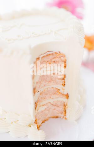 A slice of vanilla layered cake with whipped frosting and colorful ...
