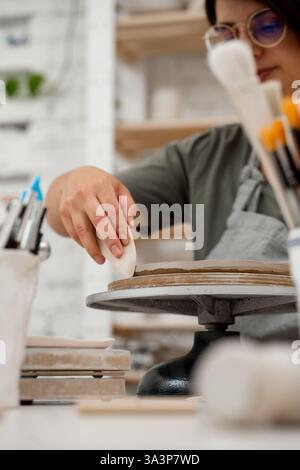 Girl is using a pottery scrapper to smooth the edges of a clay p Stock ...