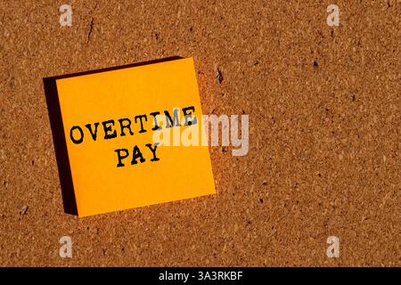 Overtime pay message written on ripped torn pink paper on yellow ...