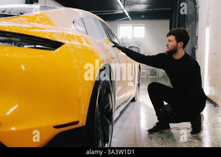 Hand cleaning of sports car using sponge and foam at the car wash ...
