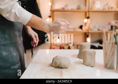 Female potter rolls piece of clay before sculpting. Preparing clay for ...
