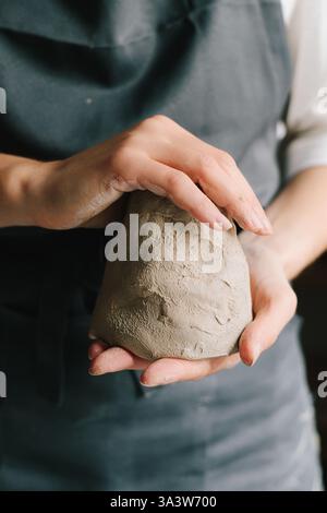 Potter holds a piece of wet clay in their hands, molds it into form ...