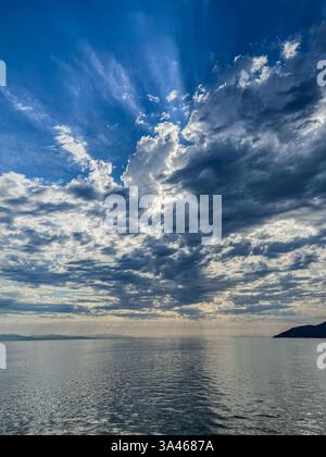 Scenic view of rippling sea water near mountain ridge against cloudy ...
