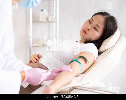 Female anesthesiologist injecting anesthetic into a vein on her arm ...