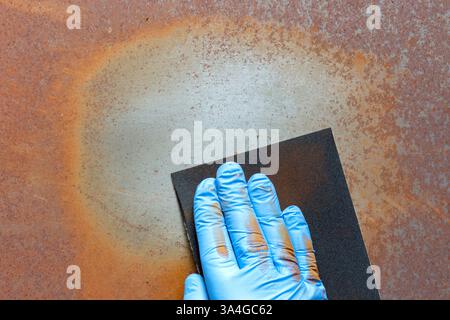 Sanding rust off sheet steel with fine grit wet and dry sandpaper ...