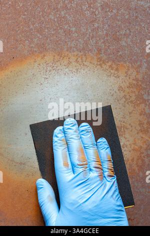 Sanding rust off sheet steel with fine grit wet and dry sandpaper ...