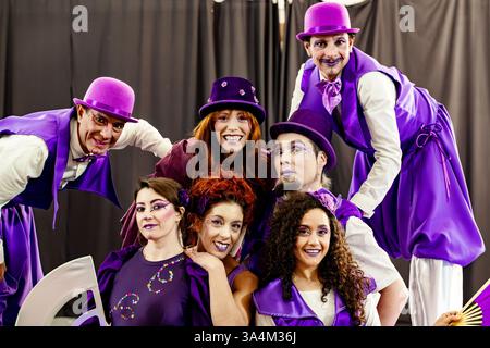 Group of smiling circus performers wearing purple costumes and makeup ...