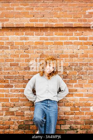happy redhead woman with curly hair in checkered casual shirt presenting product, copy space ...