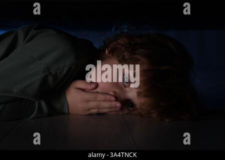 Fearful boy hiding under bed at night Stock Photo - Alamy