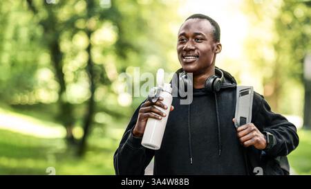 Balck guy in sport clothes holding bottle with water Stock Photo - Alamy