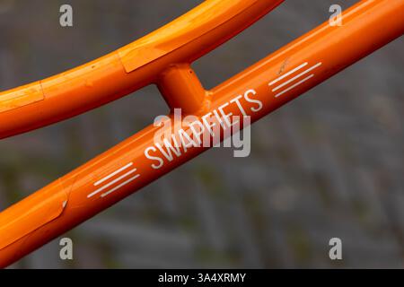 Detail of the Swapfiets logo on an orange bike parked in the city ...