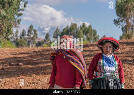 Couple of aged Peruvian farmers in bright traditional clothes standing ...