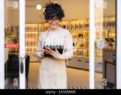 Young hispanic woman shopkeeper smiling confident holding shopping bag ...