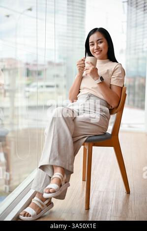 Charming asian business woman drinking coffee standing near windows at ...