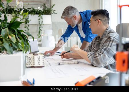 Men working with 3D printer and blueprint for designing mechanical ...