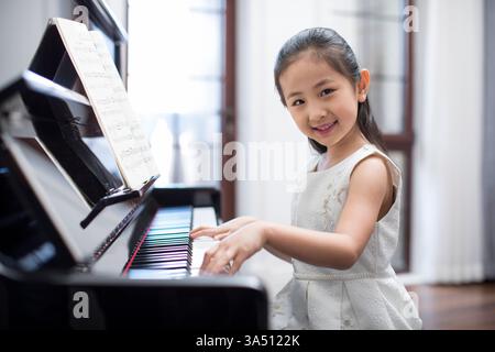 Smiling girl practicing piano at home Stock Photo - Alamy