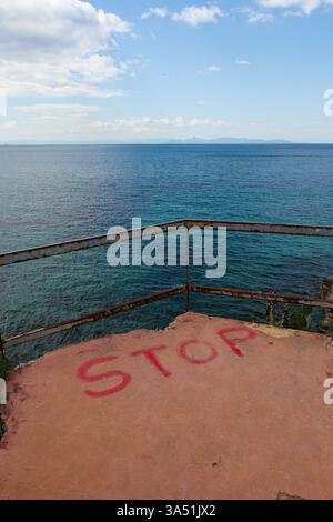 A weathered concrete platform with a rusted metal railing stands over ...